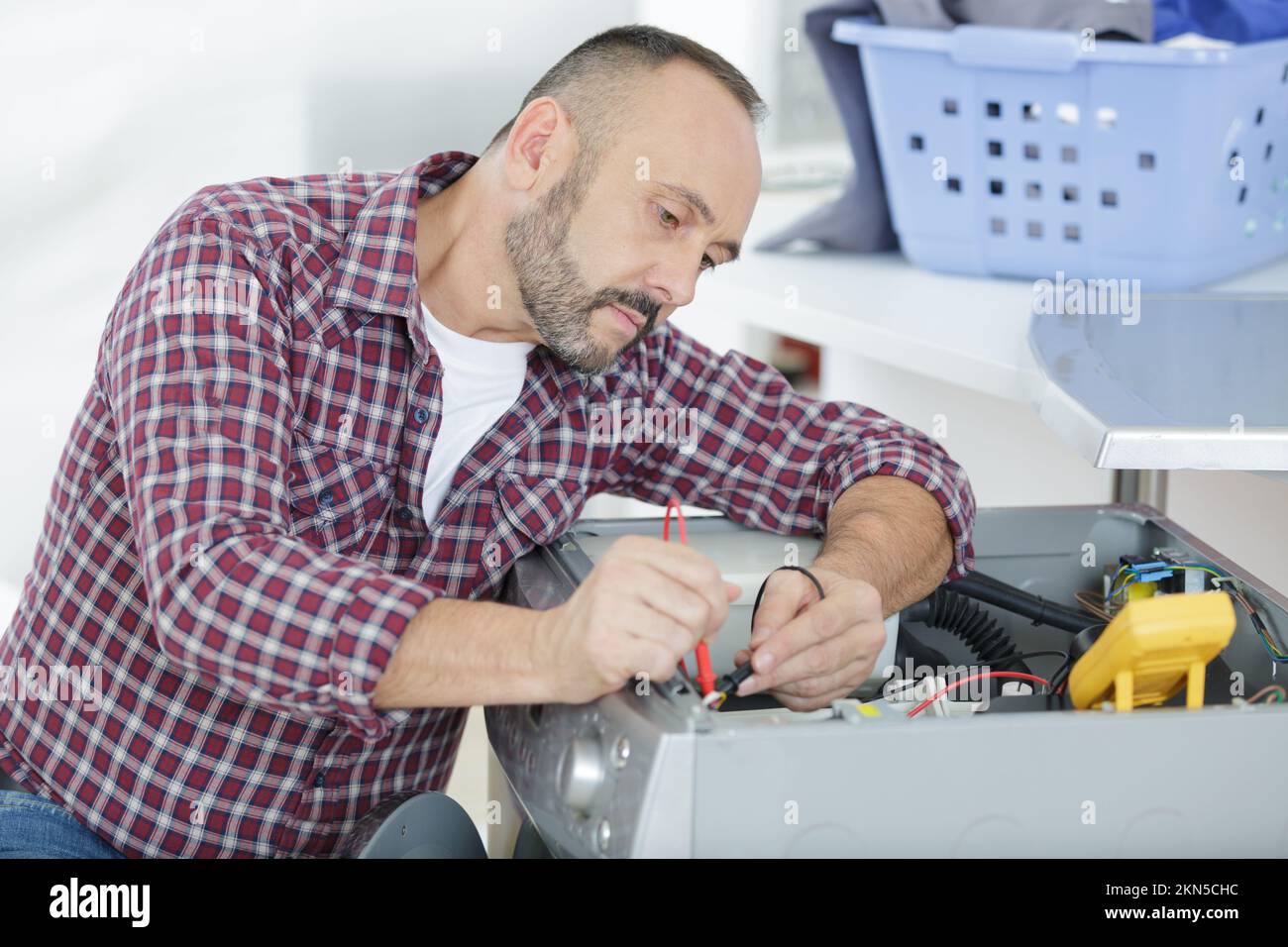 male technician inspecting and fixing a washer and dryer Stock Photo ...