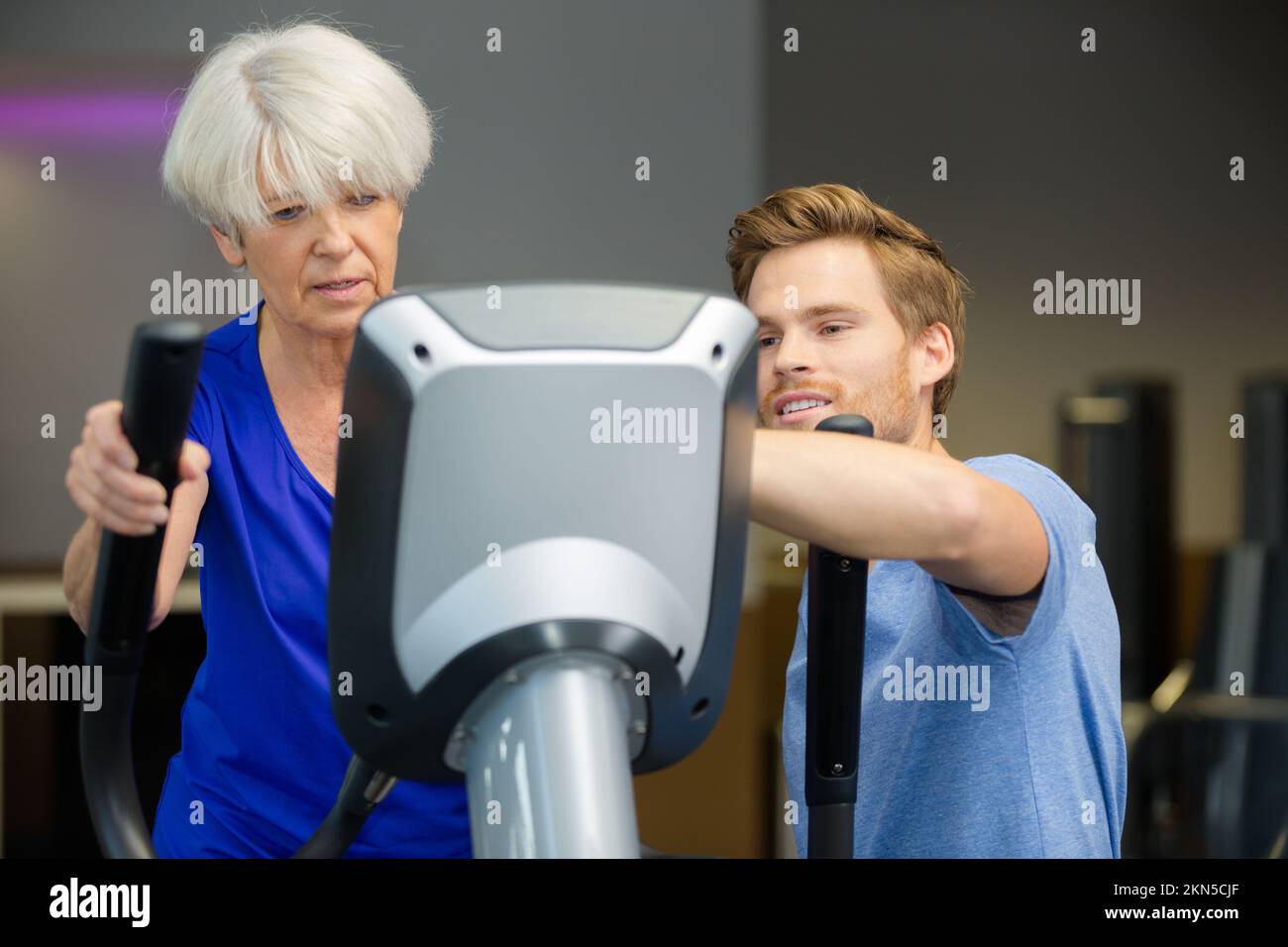 gym worker showing senior woman how to use exercise machine Stock Photo ...
