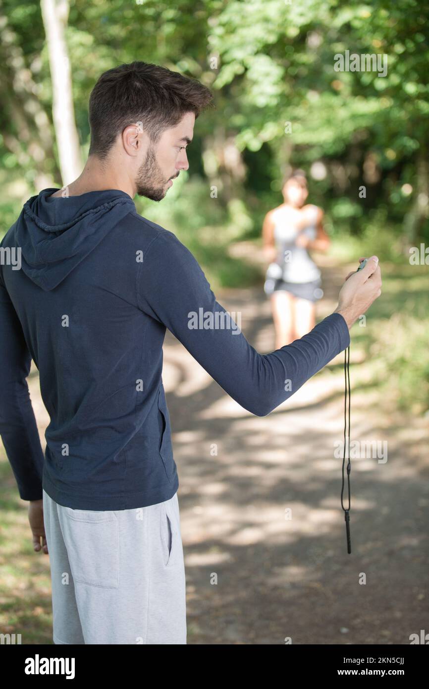 personal trainer timing a female runner Stock Photo - Alamy