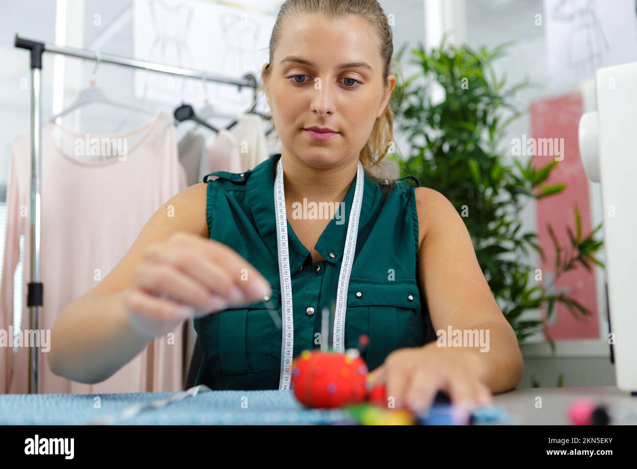 dressmaker putting pin into pin cushion Stock Photo - Alamy
