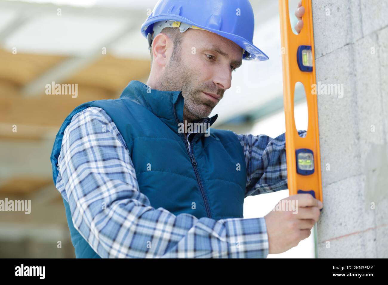 bricklayer using a spirit level to check wall level Stock Photo - Alamy