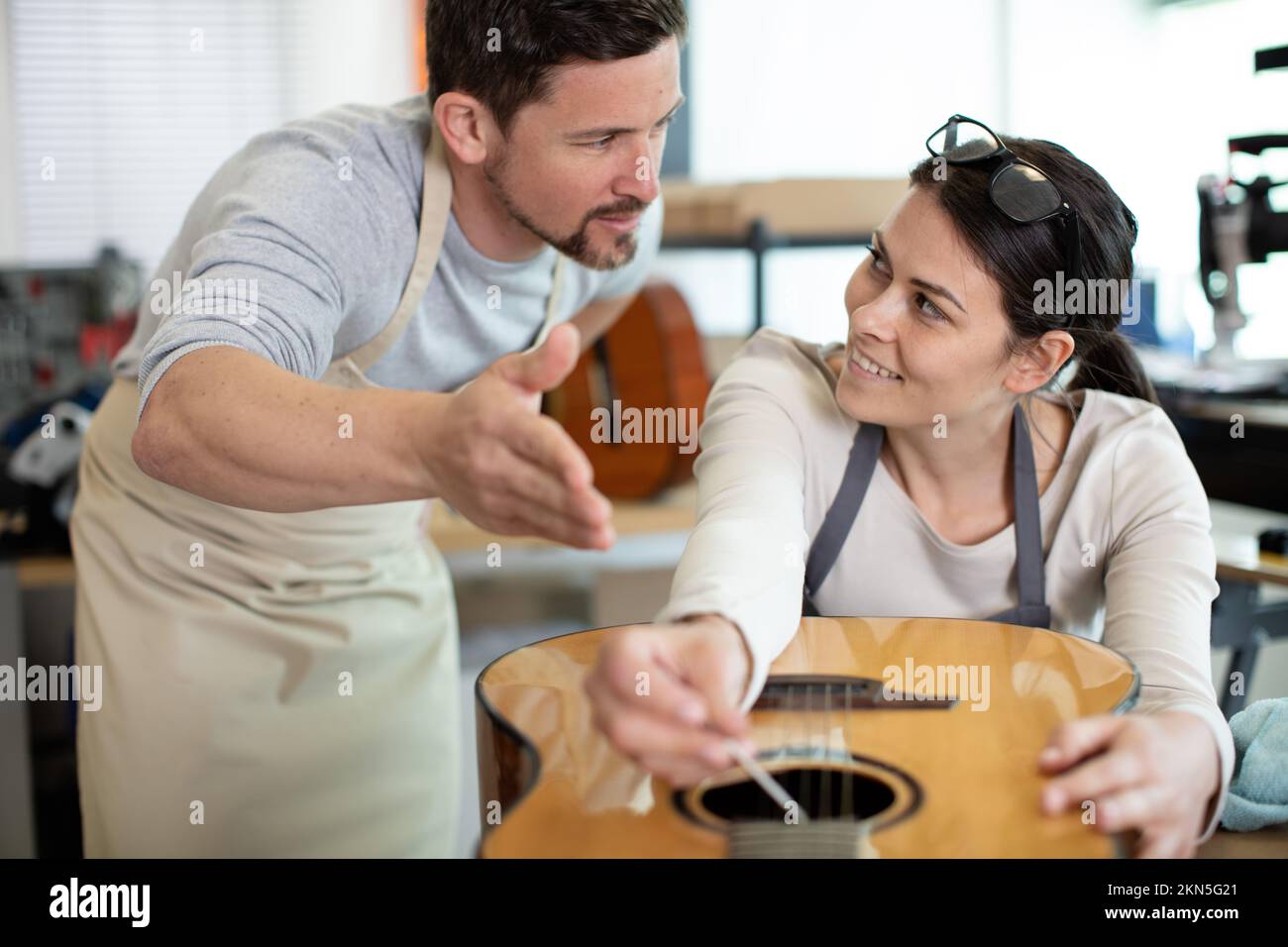 two young people fixing guitars Stock Photo - Alamy
