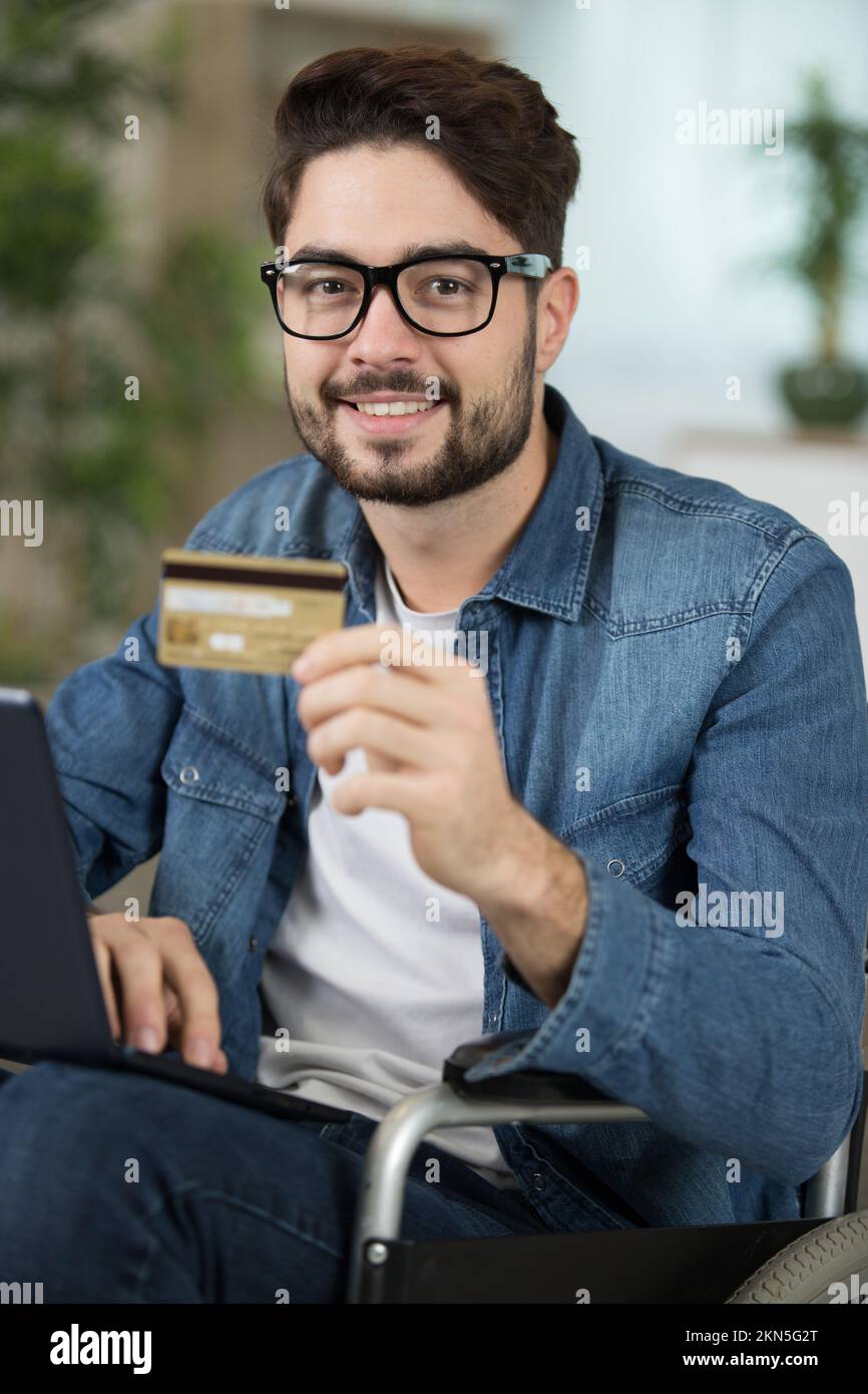 disabled person holds credit card and uses pc Stock Photo - Alamy