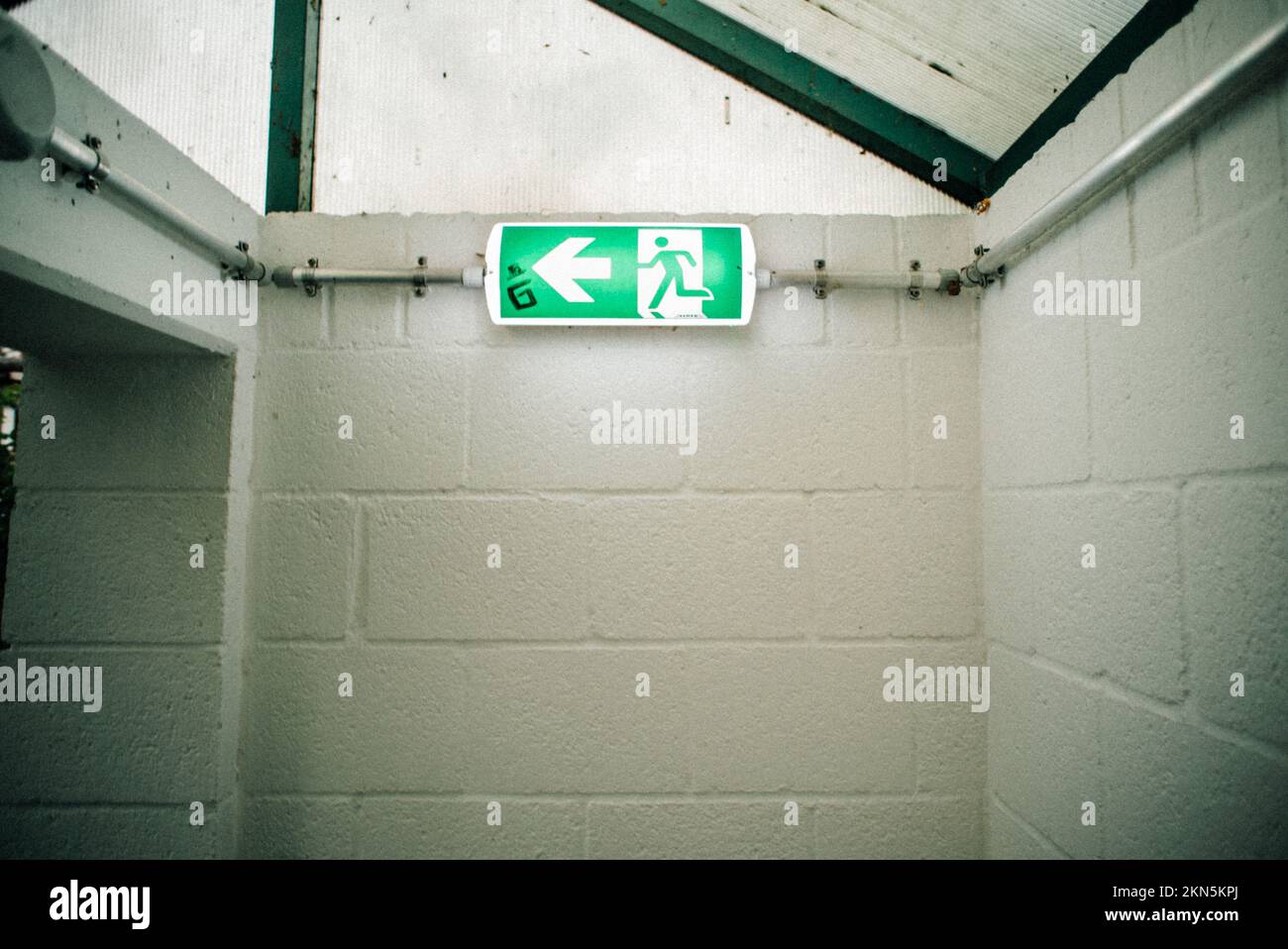 A fire exit green sign on the wall Stock Photo - Alamy