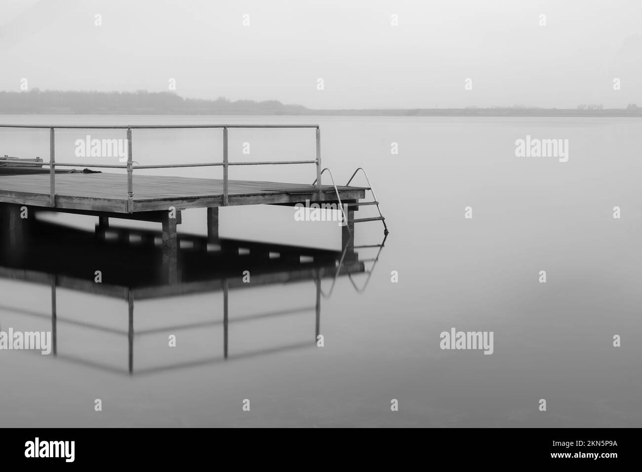 A black-and-white shot of a wooden dock as a swimming platform in a ...
