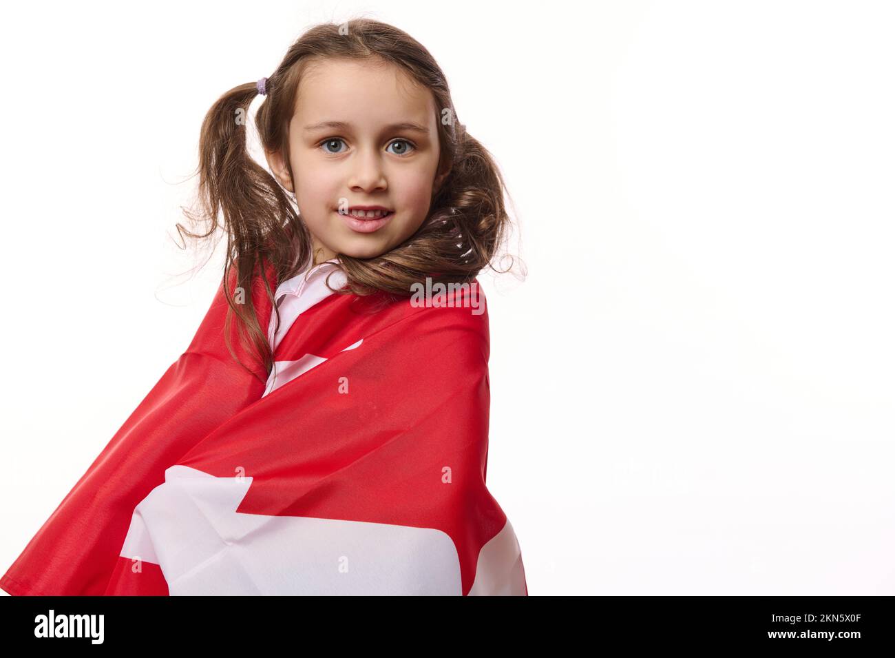 Close-up American citizen, little child girl wrapping in Canadian flag ...