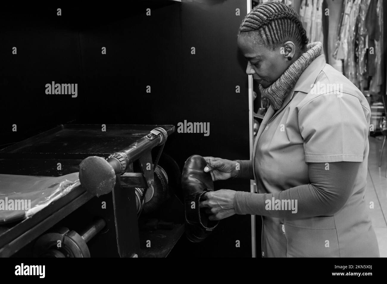 A grayscale shot of an African woman working in a shoe repair and dry ...