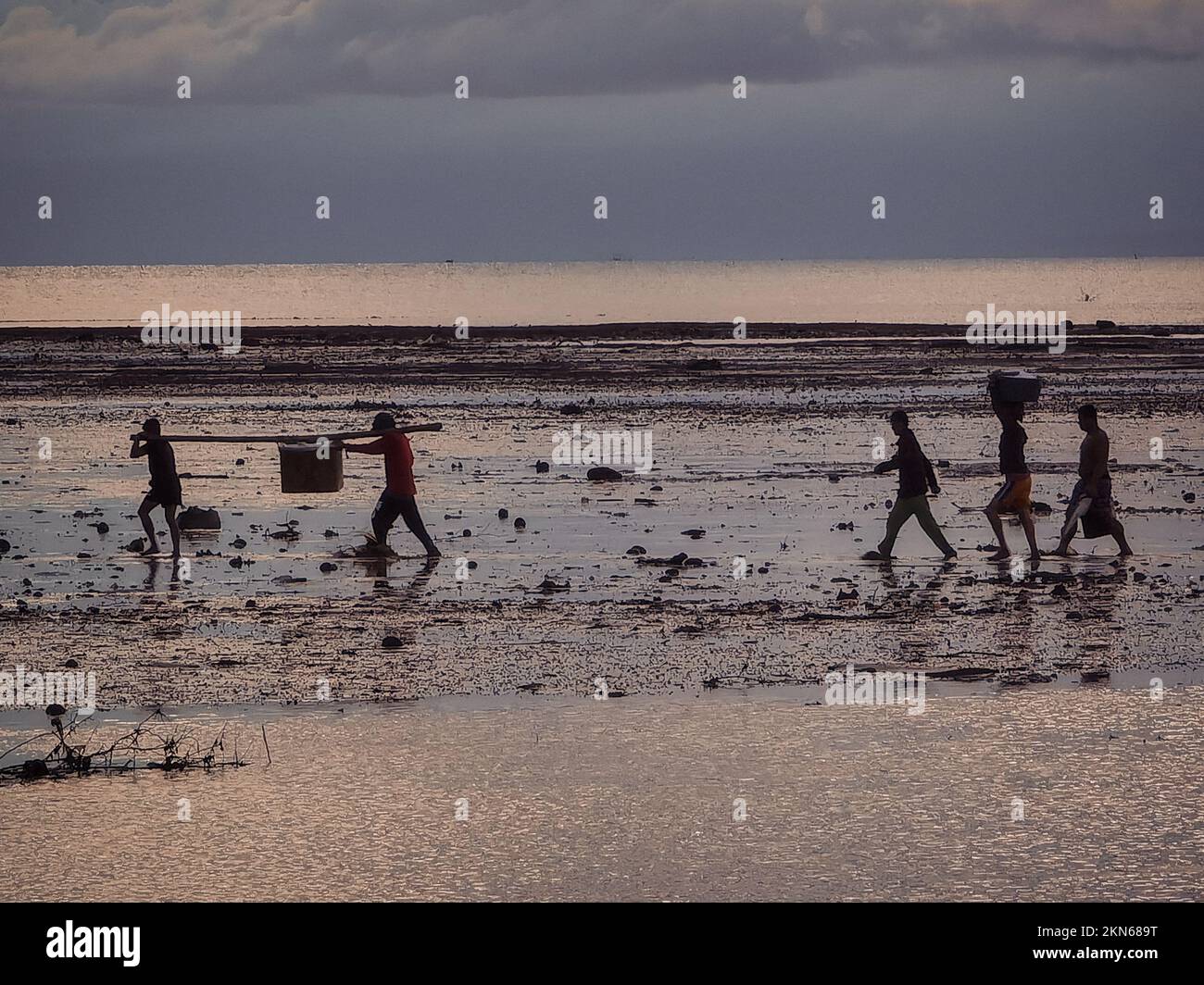 Traditional people holding fishing pots on the beach by water in Manual ...