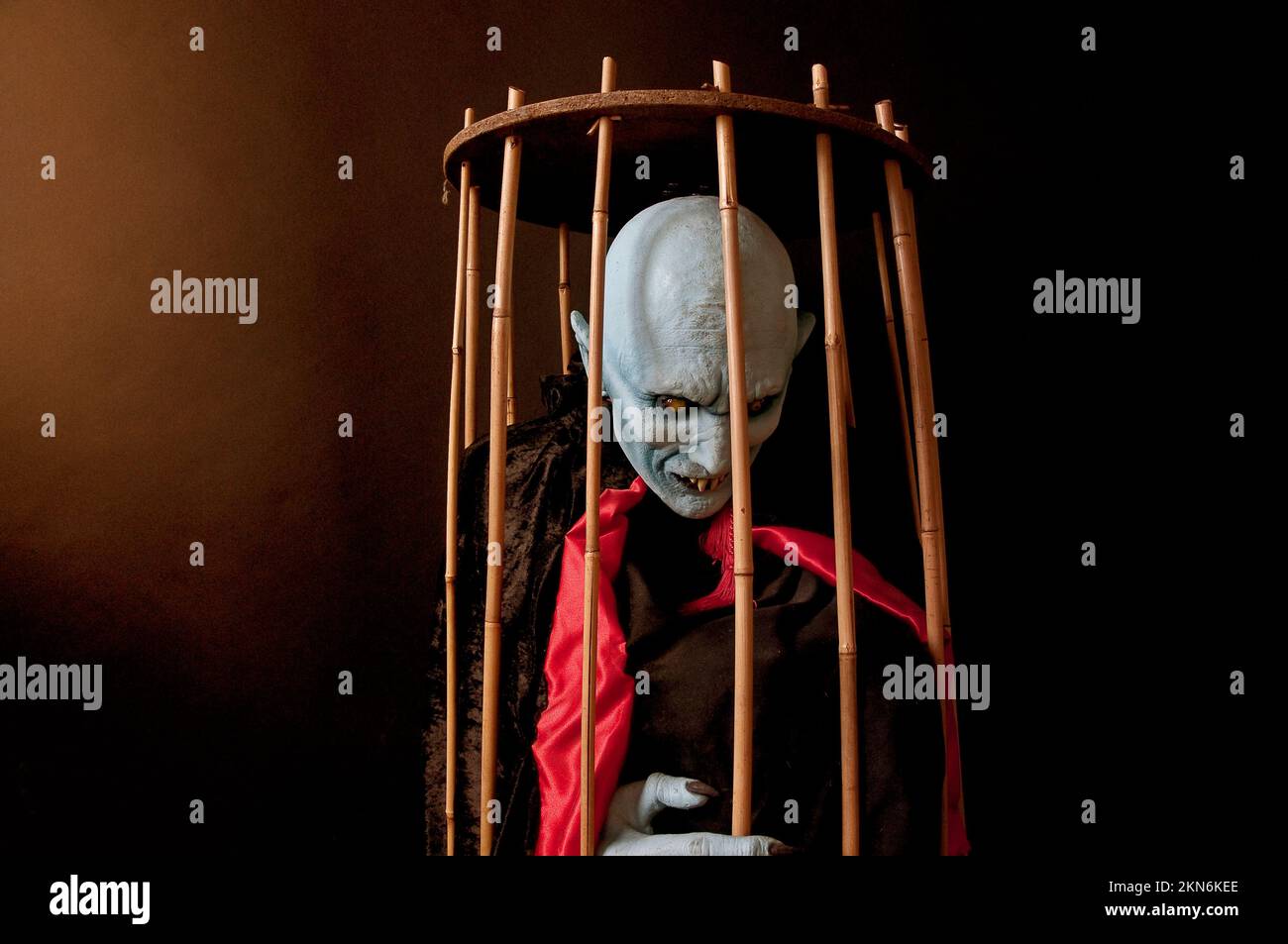 A scary portrait of a rubber Dracula looking down inside metal cage ...