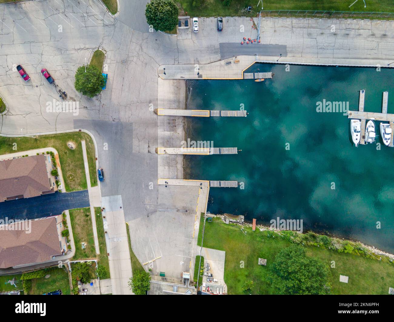 An aerial top view of a harbor surrounded by houses, grass and roads ...