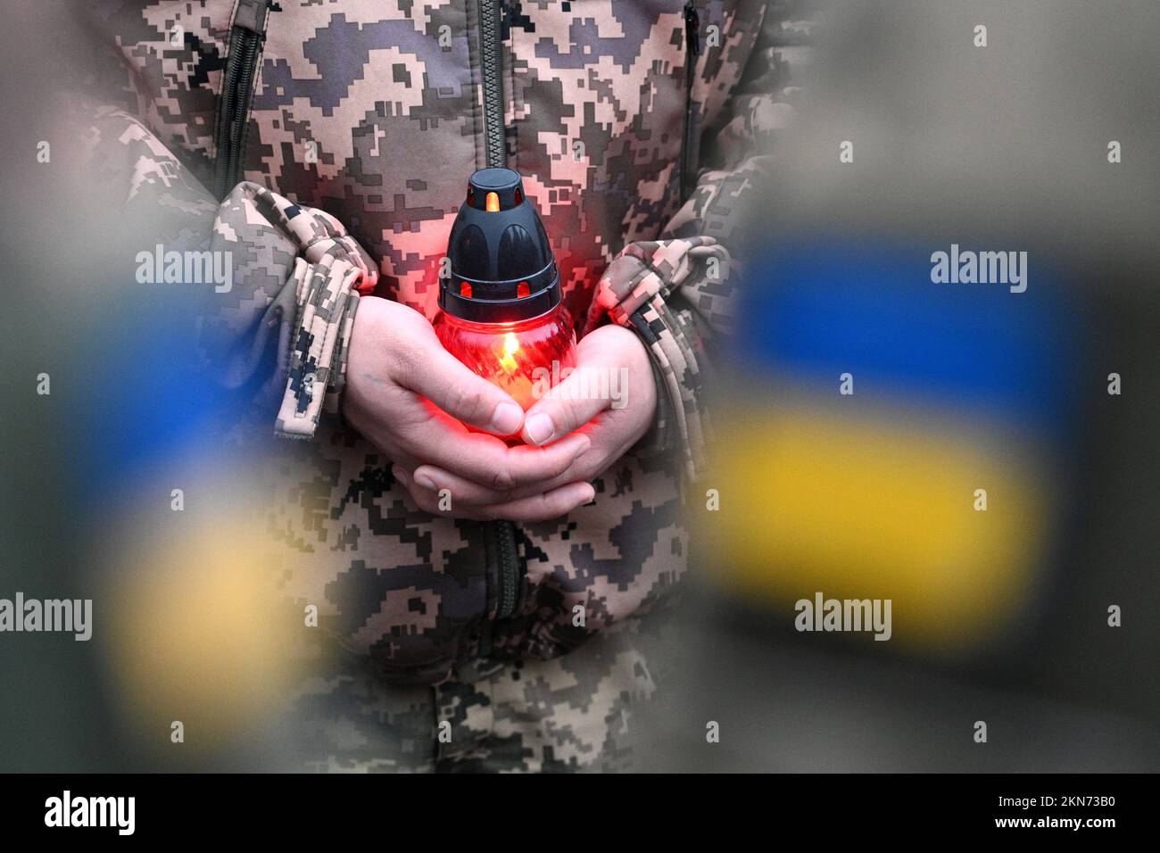 A Ukrainian seviceman holds a candle. Ukrainian flag on military ...