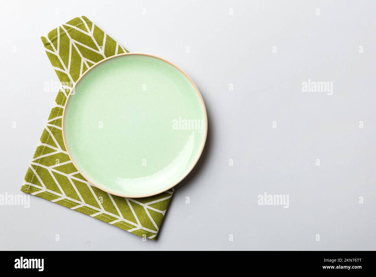 Top view on colored background empty round green plate on tablecloth ...