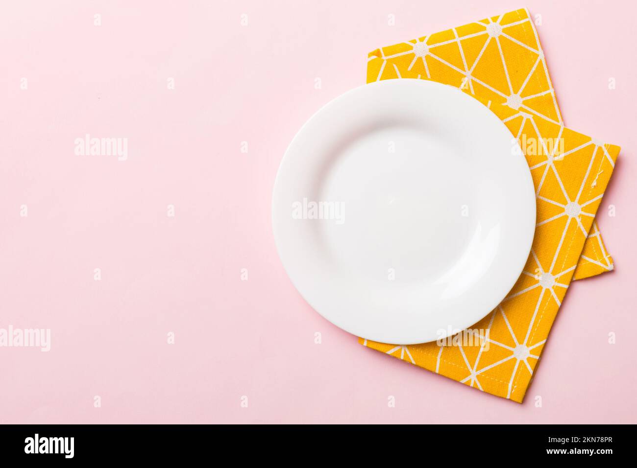 Top view on colored background empty round white plate on tablecloth ...