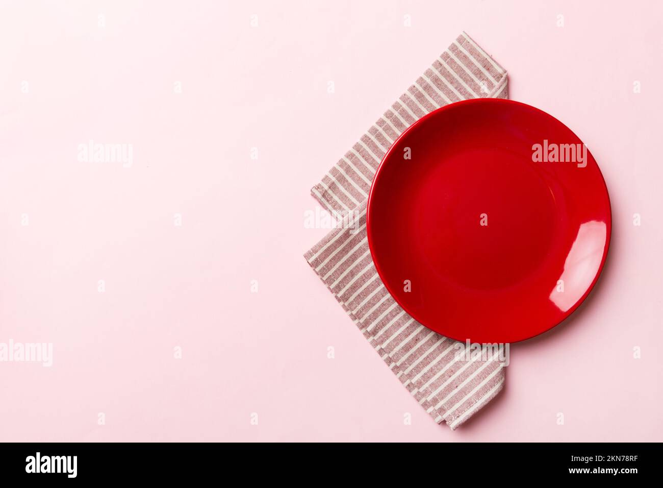 Top view on colored background empty round red plate on tablecloth for ...