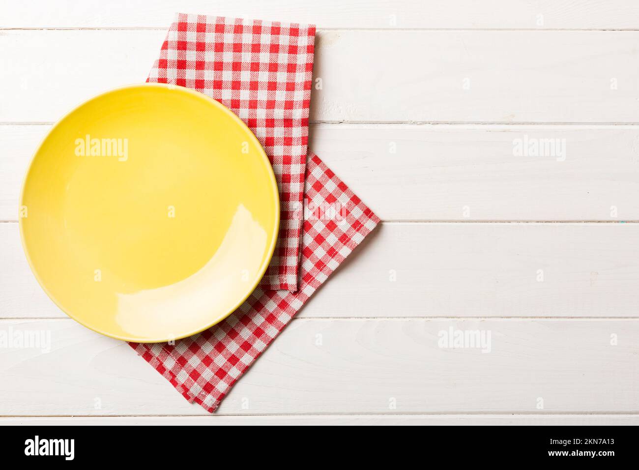 Top view on colored background empty round yellow plate on tablecloth ...