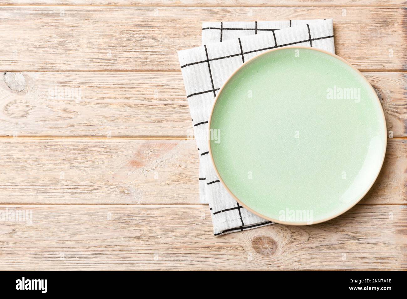 Top view on colored background empty round green plate on tablecloth ...