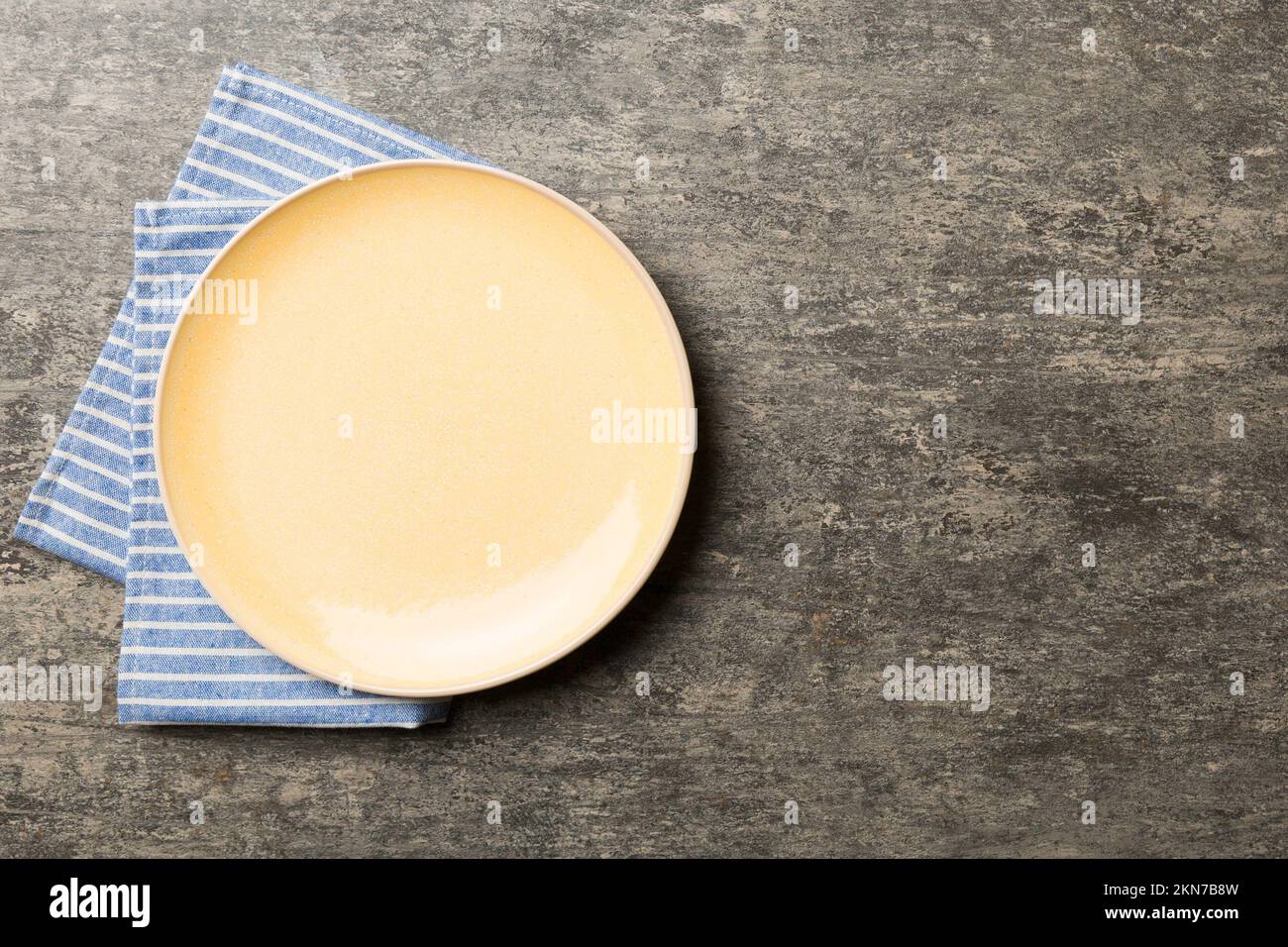 Top view on colored background empty round yellow plate on tablecloth ...