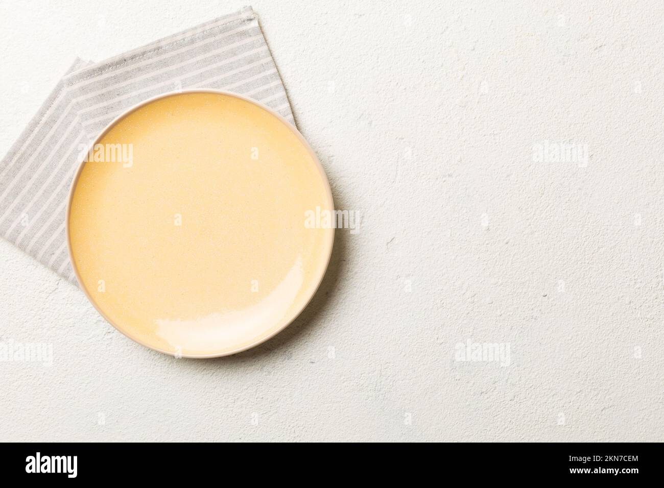 Top view on colored background empty round yellow plate on tablecloth ...