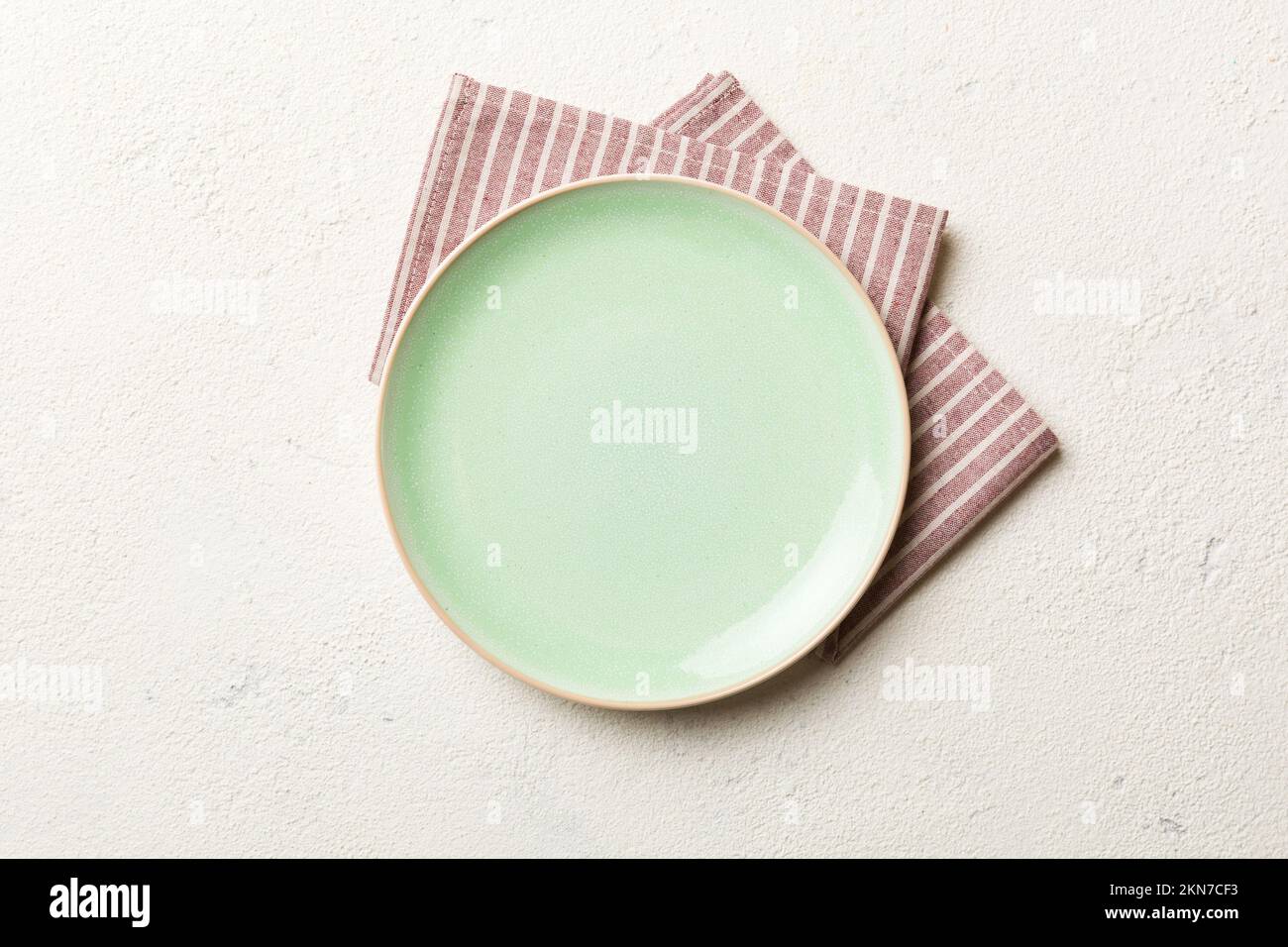 Top view on colored background empty round green plate on tablecloth ...