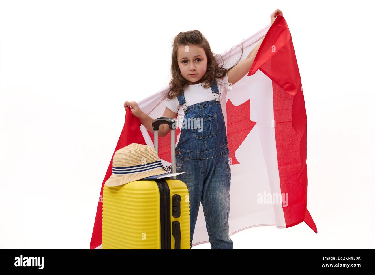 Little girl in white t-shirt and blue denim overalls, carrying Canada ...