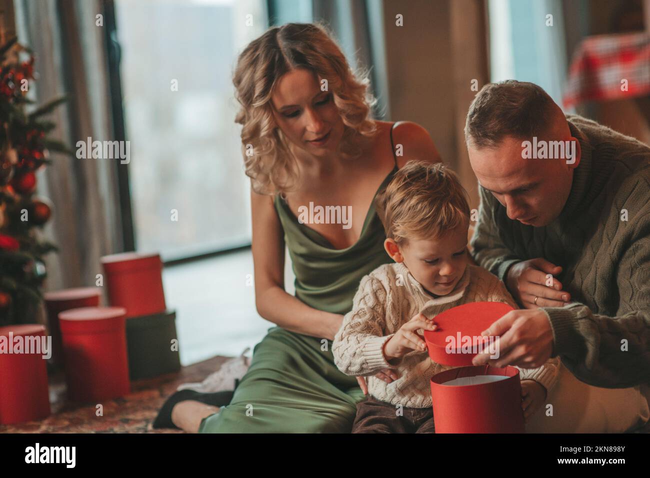 Portrait of happy family in knitted beige sweaters waiting Santa indoor ...