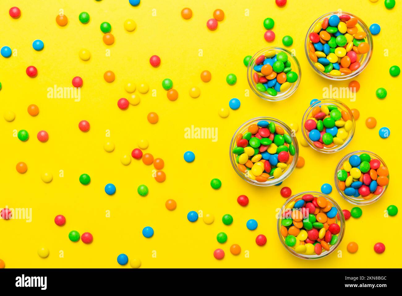 different colored round candy in bowl and jars. Top view of large ...