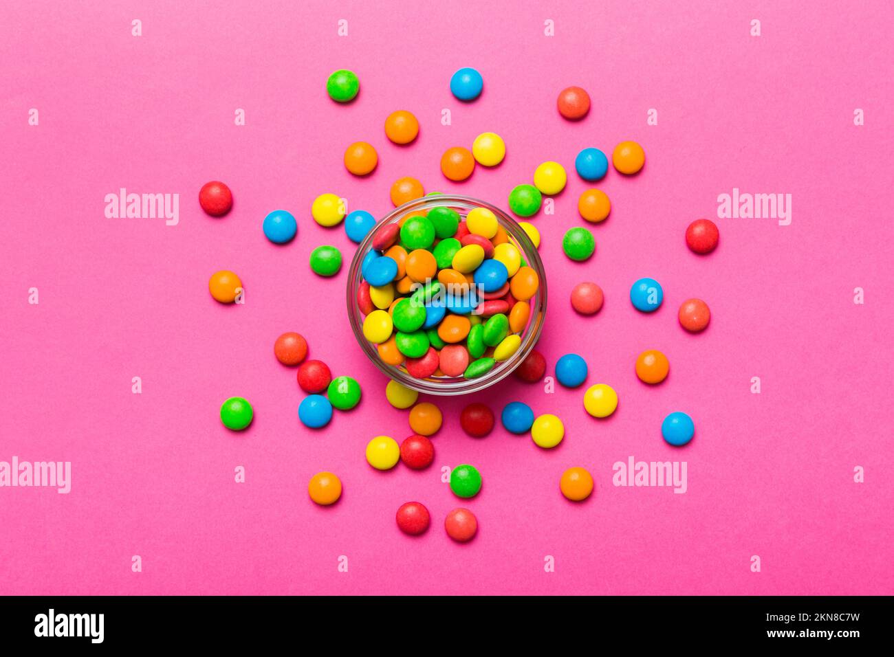 different colored round candy in bowl and jars. Top view of large ...