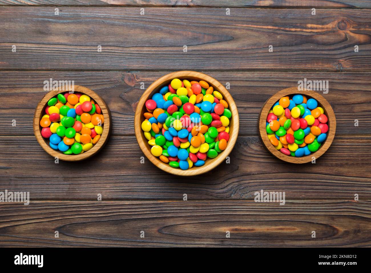 different colored round candy in bowl and jars. Top view of large ...