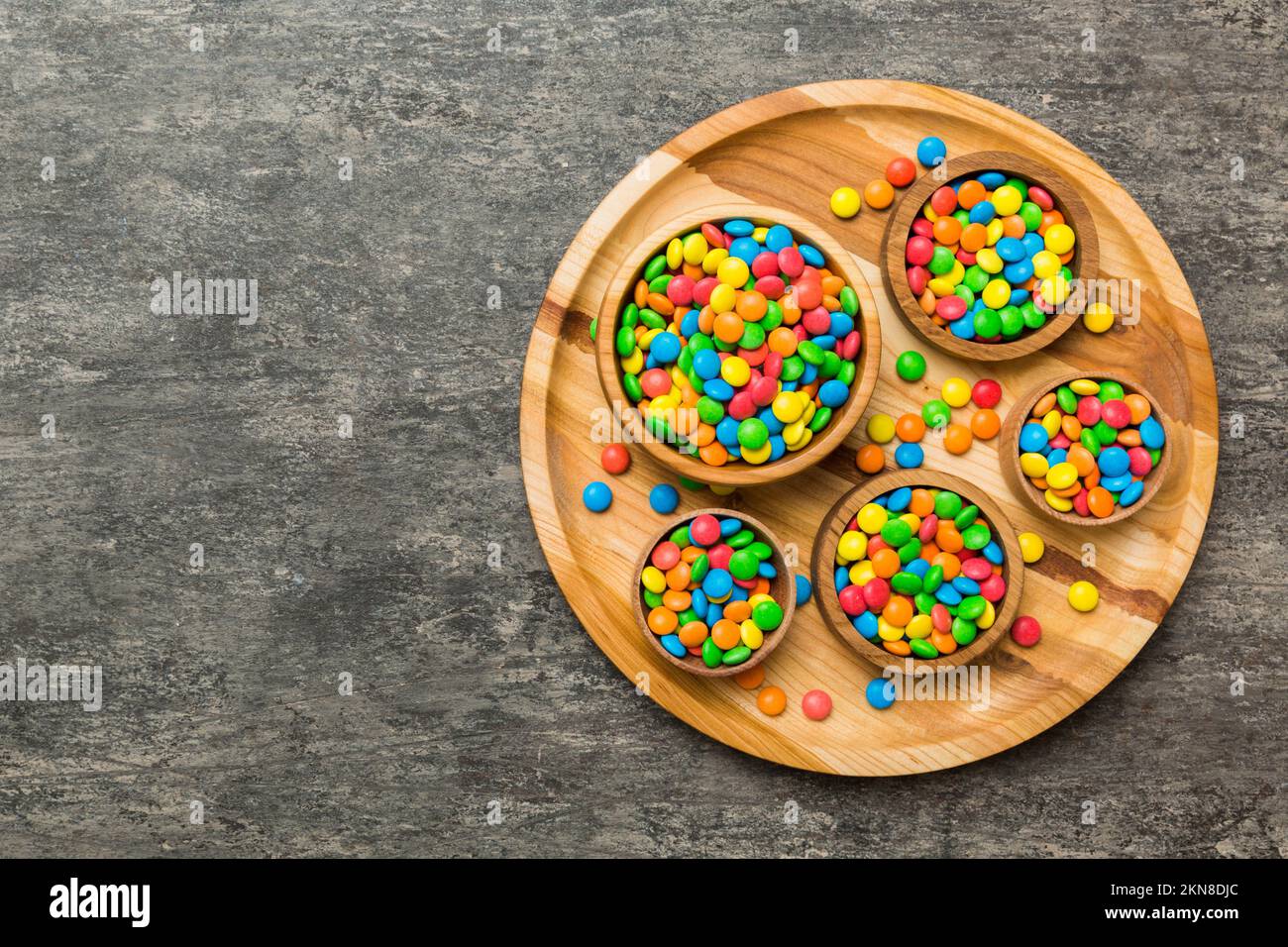 different colored round candy in bowl and jars. Top view of large ...