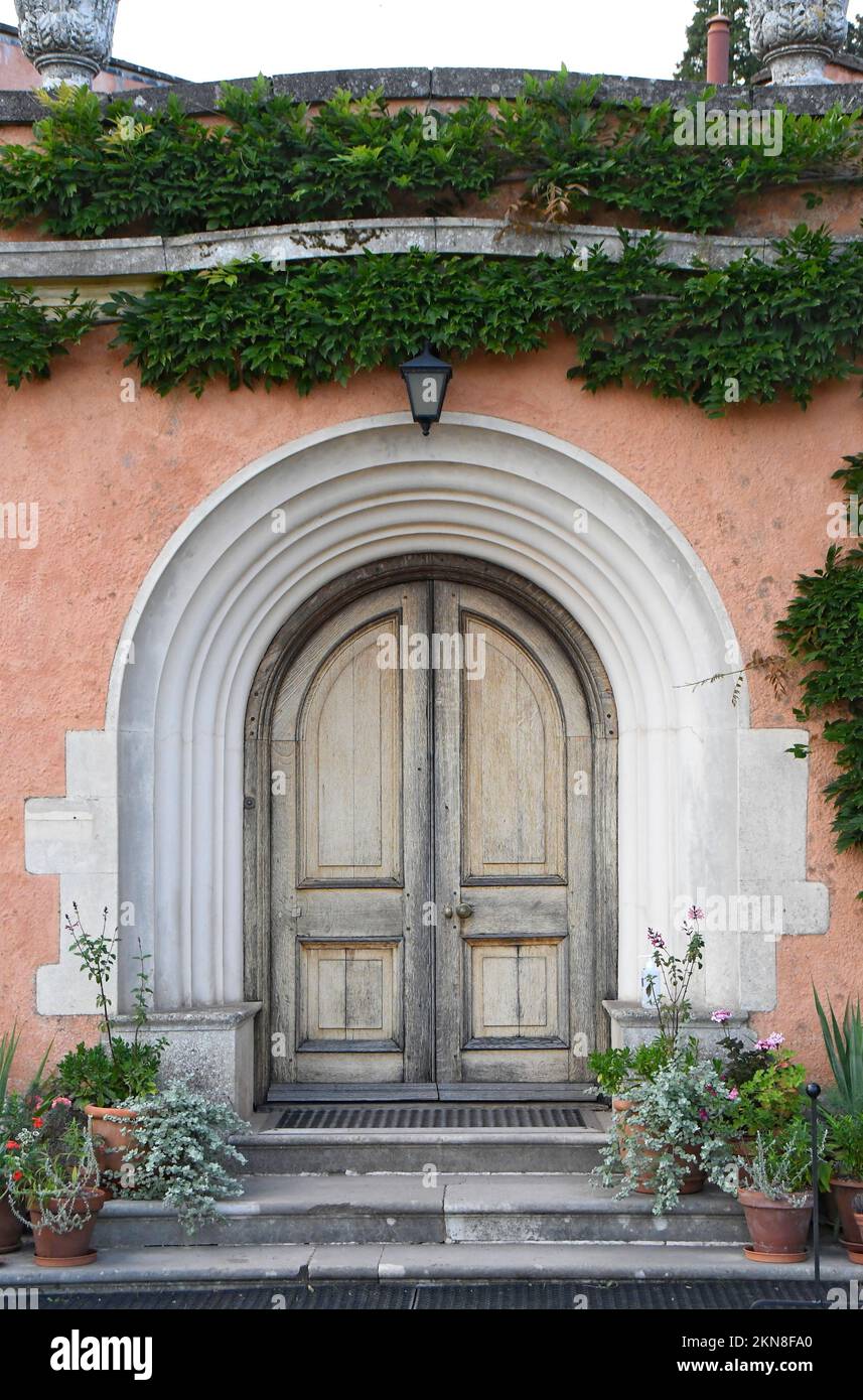 A large old arched entrance doorway with a set of timber double doors ...