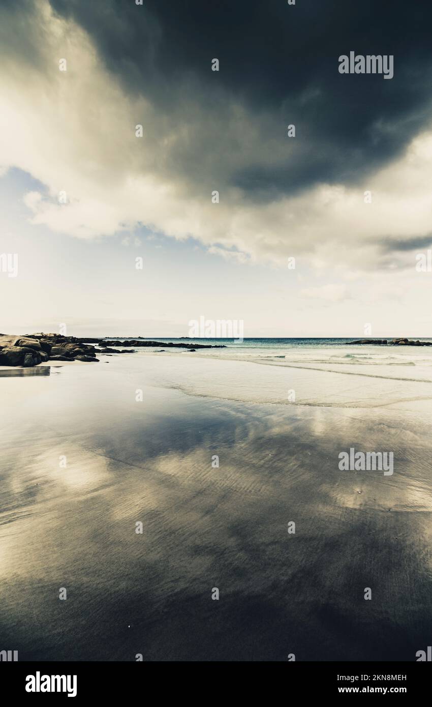 Mirrored seaside landscape reflecting grey skies of an oncoming storm ...