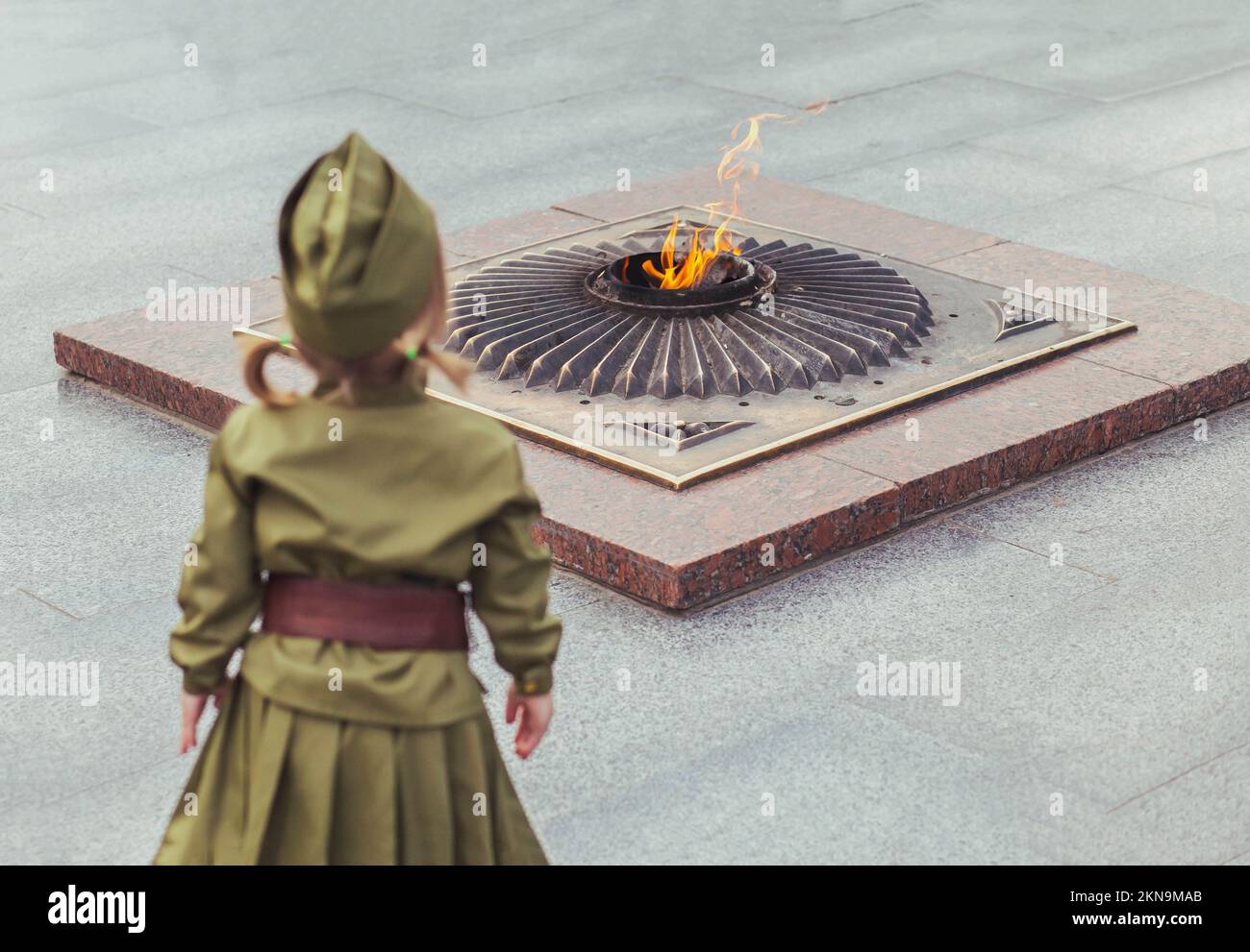 baby in Soviet military uniform looks at the monument of World War II ...