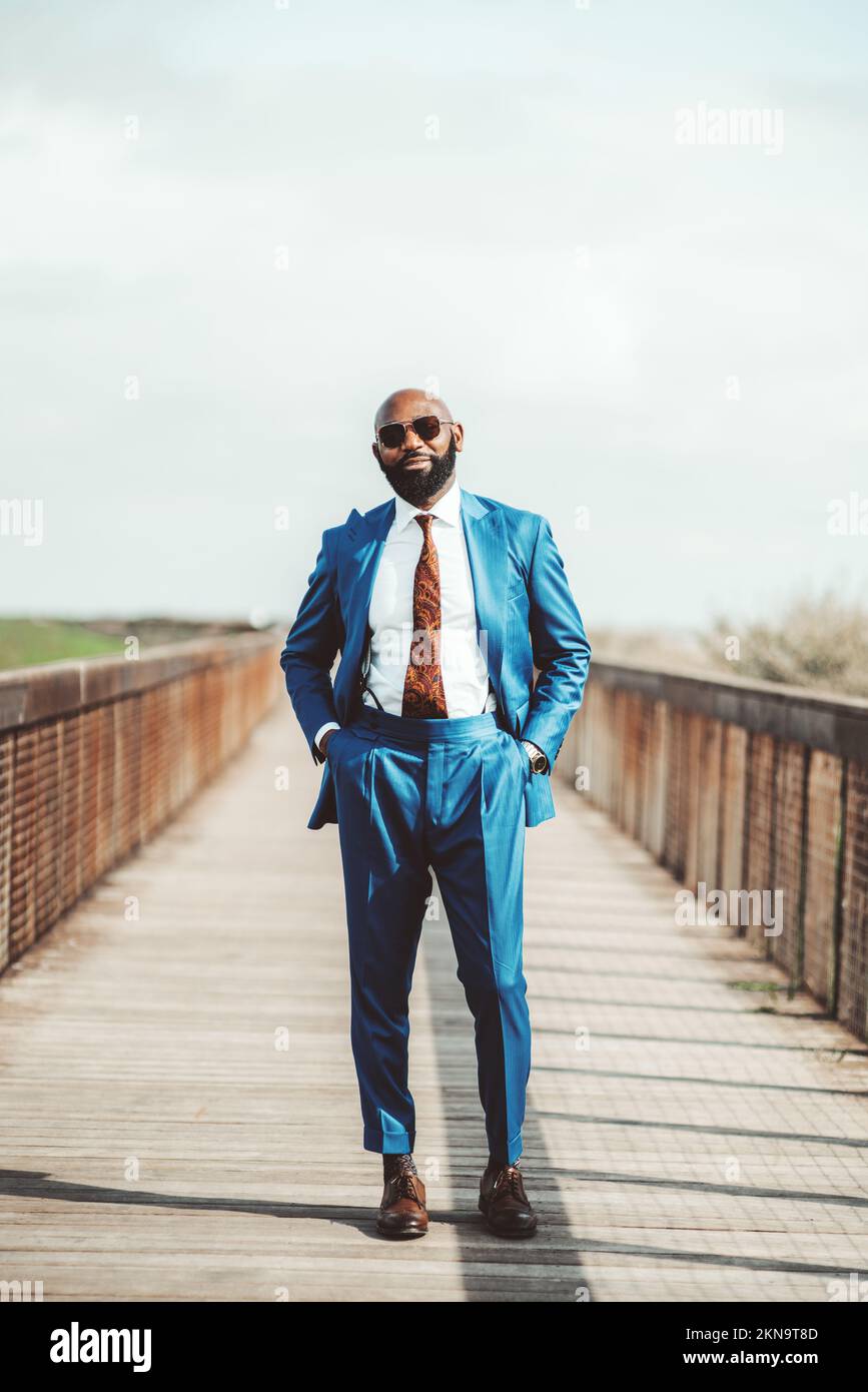 Selective focus on a tall bald African gentleman in a blue suit with a ...