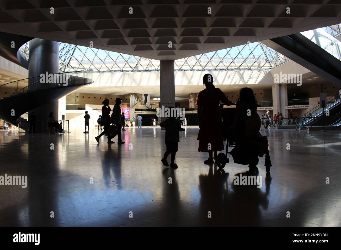 Silhouettes of people inside the Louvre Museum's Main Atrium beneath ...