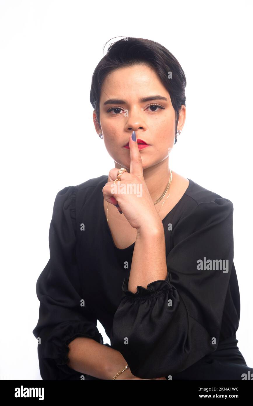 Young, elegant businesswoman making silence sign with finger on mouth ...