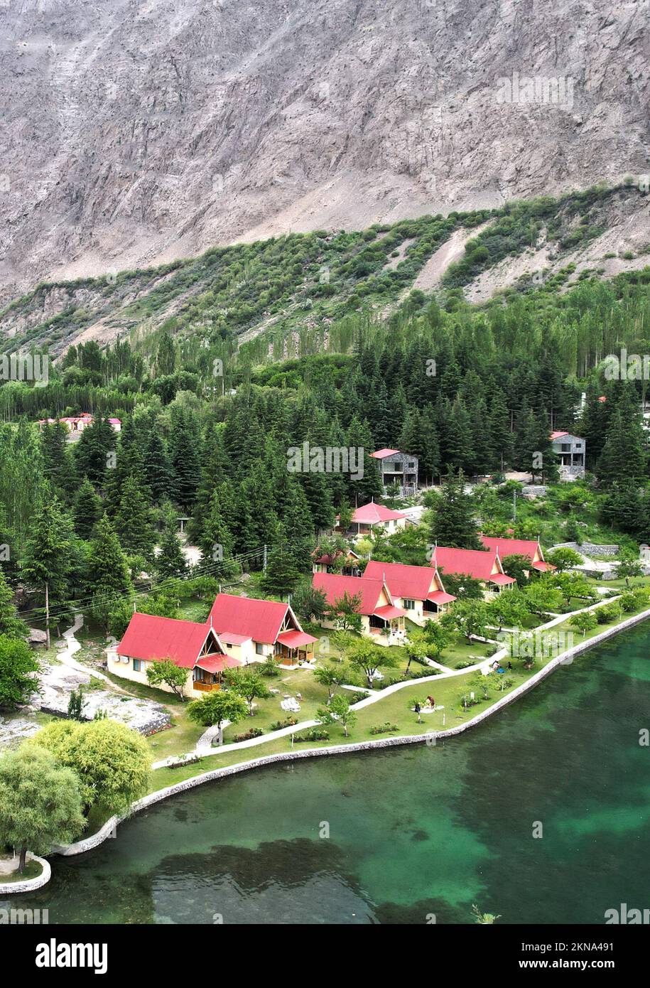 The vertical aerial view of waterside town buildings and trees before a ...