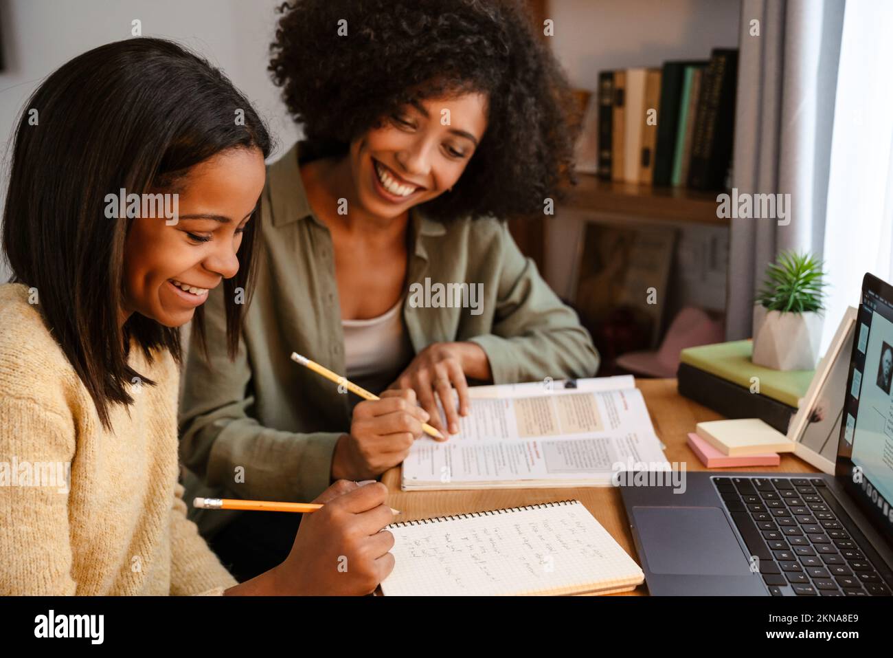 Black girl writing in exercise book while doing homework with her ...