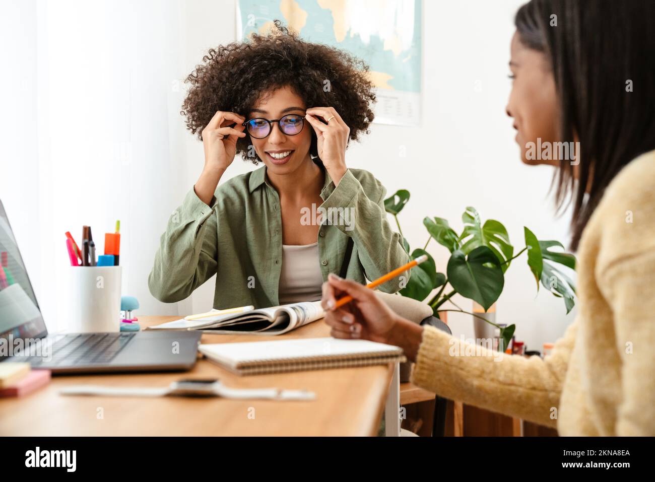Black girl writing in exercise book while doing homework with her ...