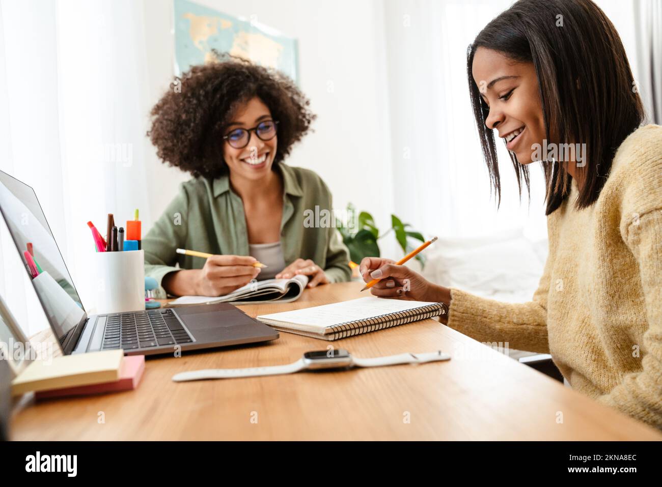 Black girl writing in exercise book while doing homework with her ...