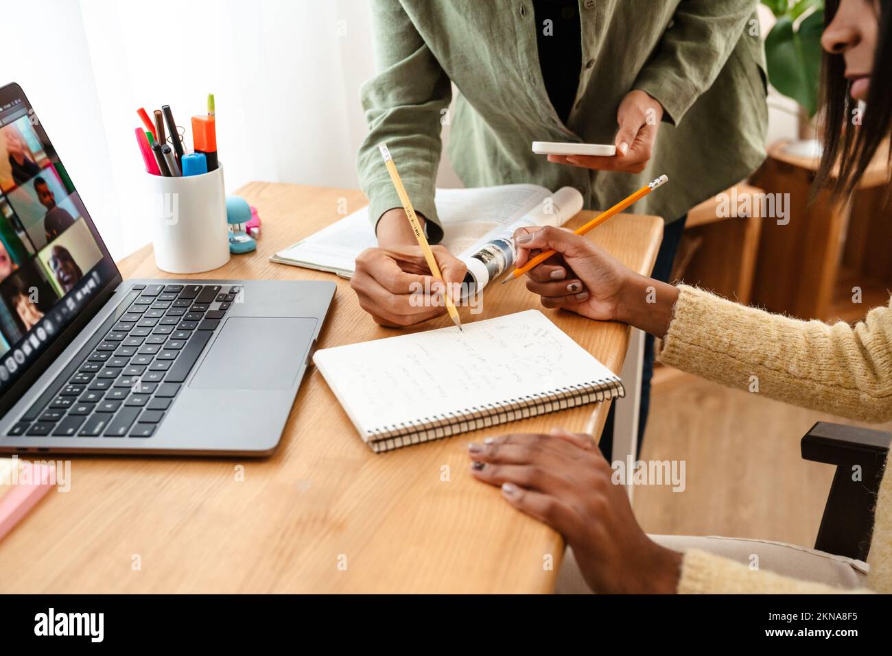Black girl writing in exercise book while doing homework with her ...