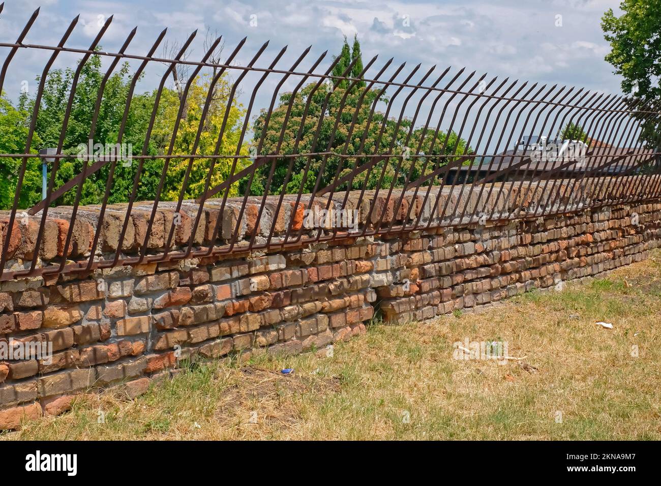 Spiked fence bars at brick wall protection safety Stock Photo - Alamy