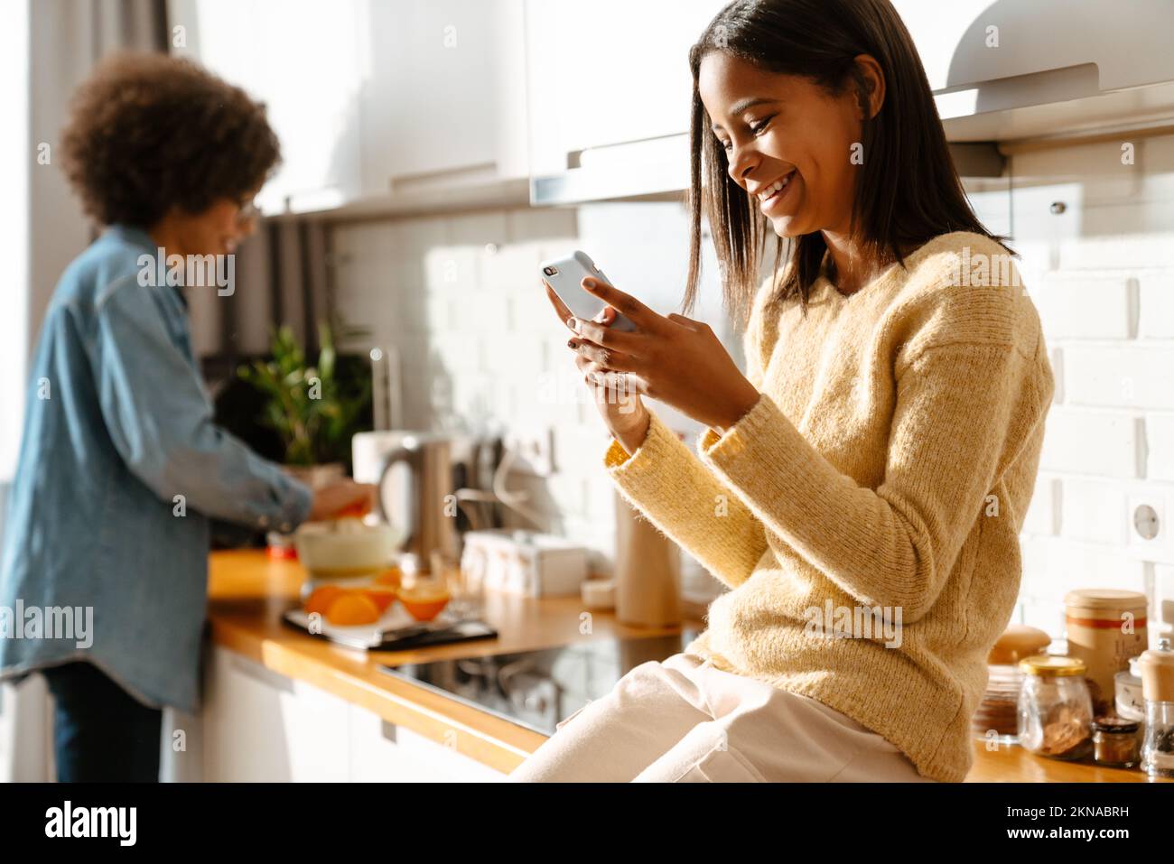 Black girl using mobile phone during spending time with her mother in ...