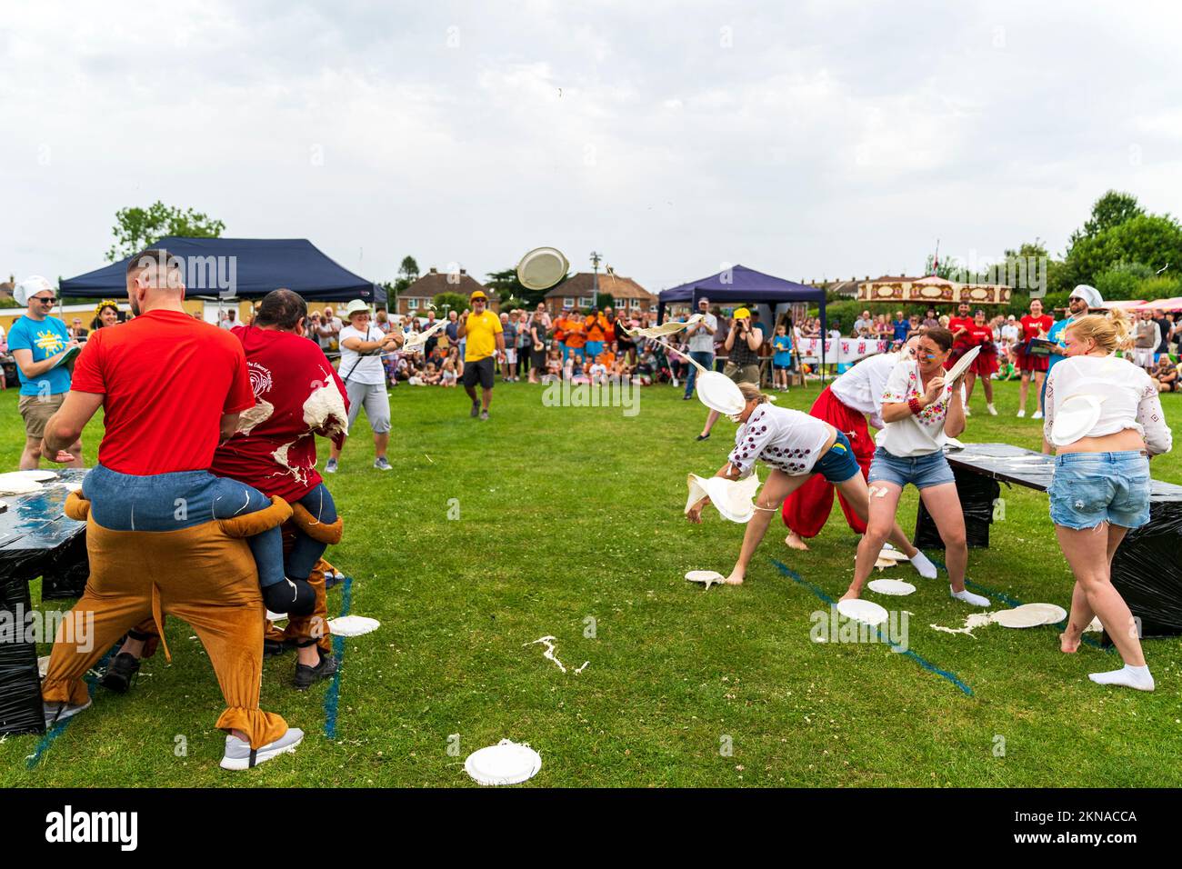 Two teams of four people throwing custard pies at each other at the ...