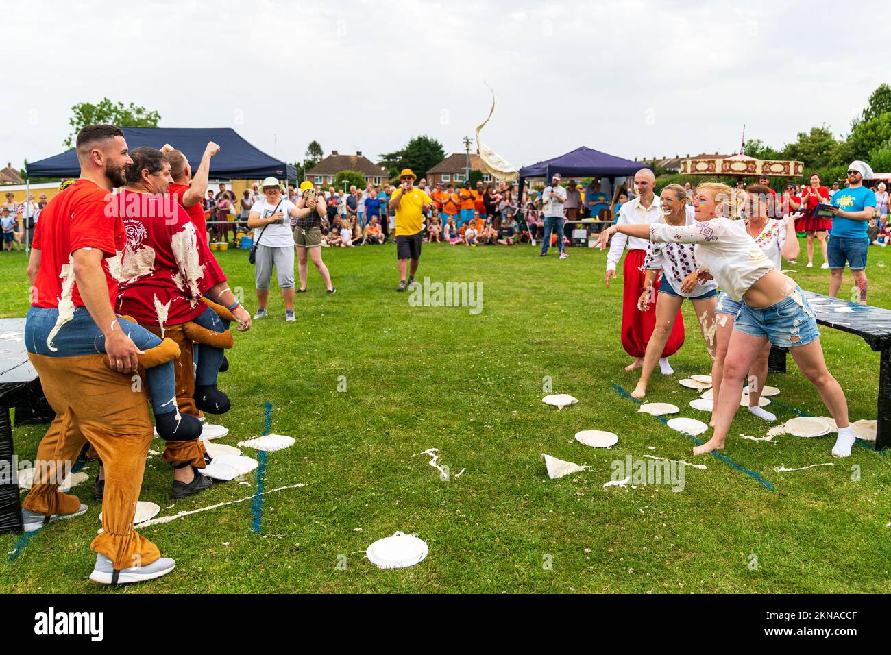 Two teams of four people throwing custard pies at each other at the ...