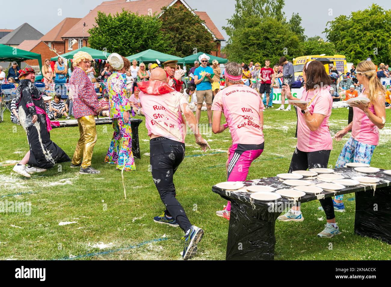 Two teams of four people throwing custard pies at each other at the ...