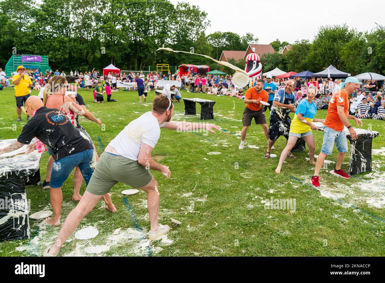 Two teams of four people throwing custard pies at each other at the ...