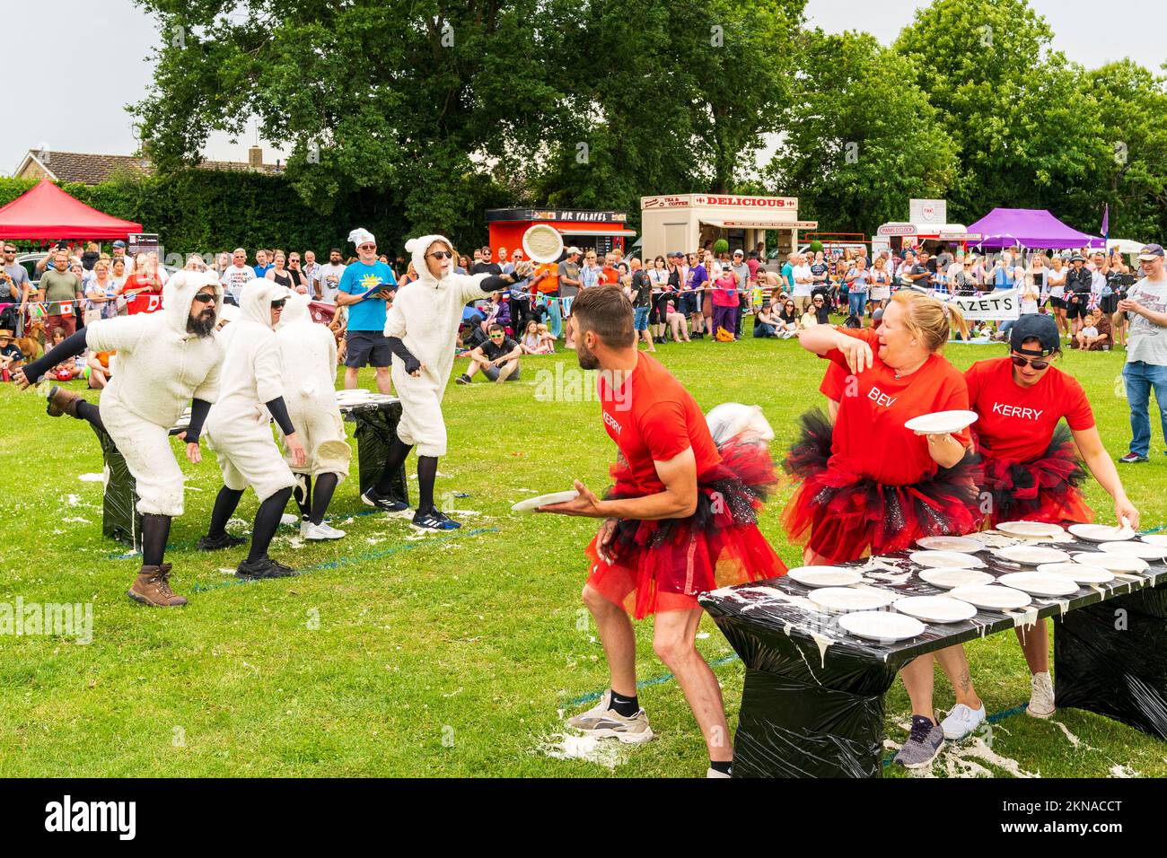 Two teams of four people throwing custard pies at each other at the ...