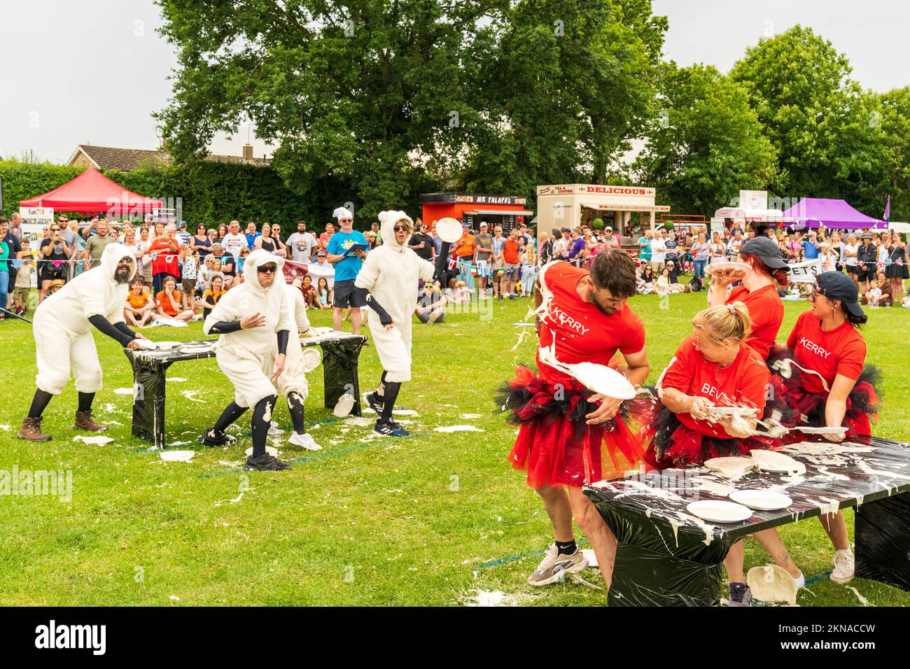 Two teams of four people throwing custard pies at each other at the ...