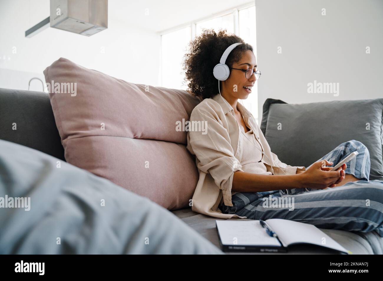 African american young woman using cellphone and headphones while ...