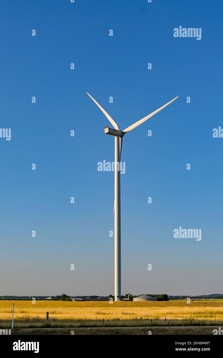 Tall wind turbine in as farm field isolated against a deep blue sky. No ...